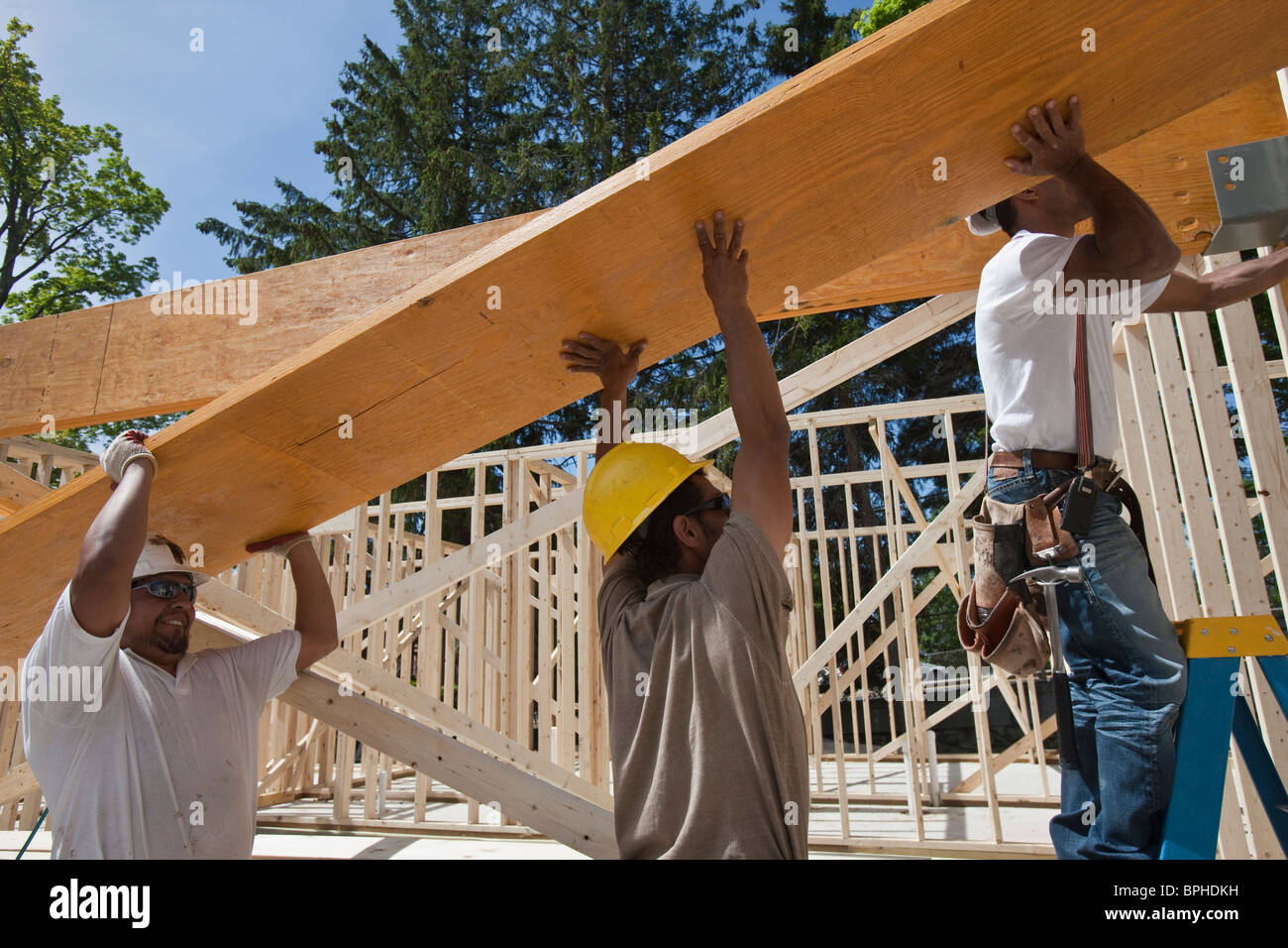 Carpenters lifting a laminated beam at a construction site Stock Photo ...