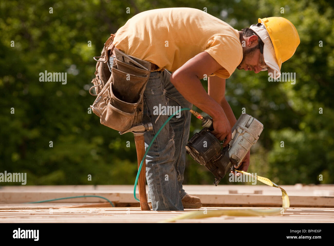 Carpenter using nail gun on wood and measuring frame Stock Photo - Alamy