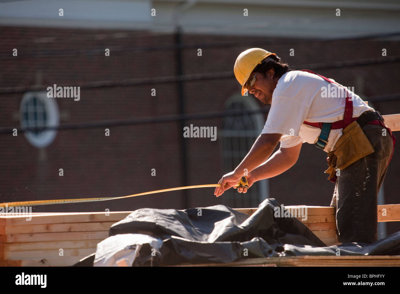 Carpenter using a tape measure at a construction site Stock Photo - Alamy