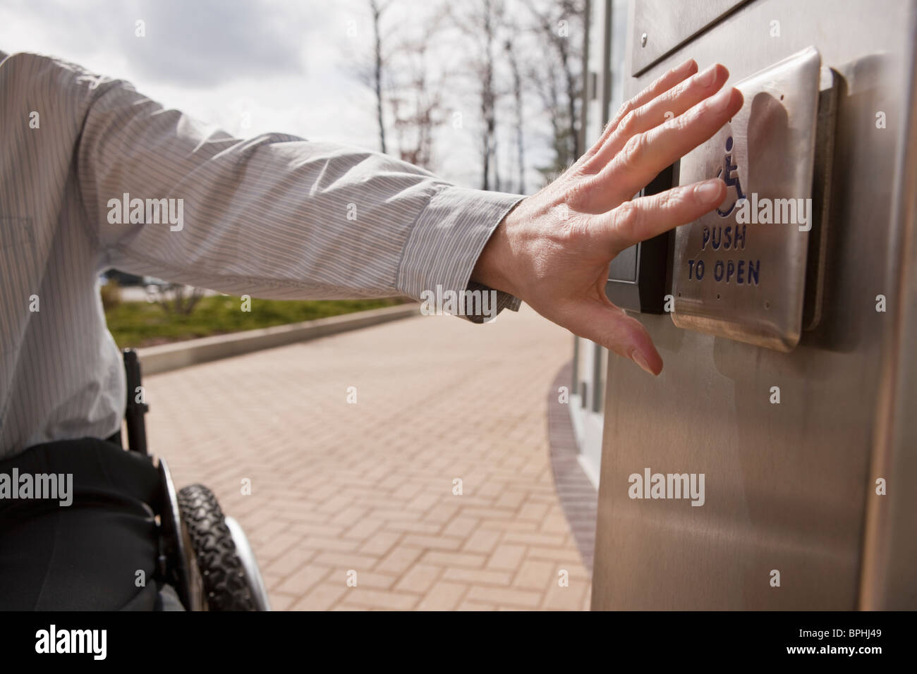Businessman with spinal cord injury in a wheelchair pushing a button to ...