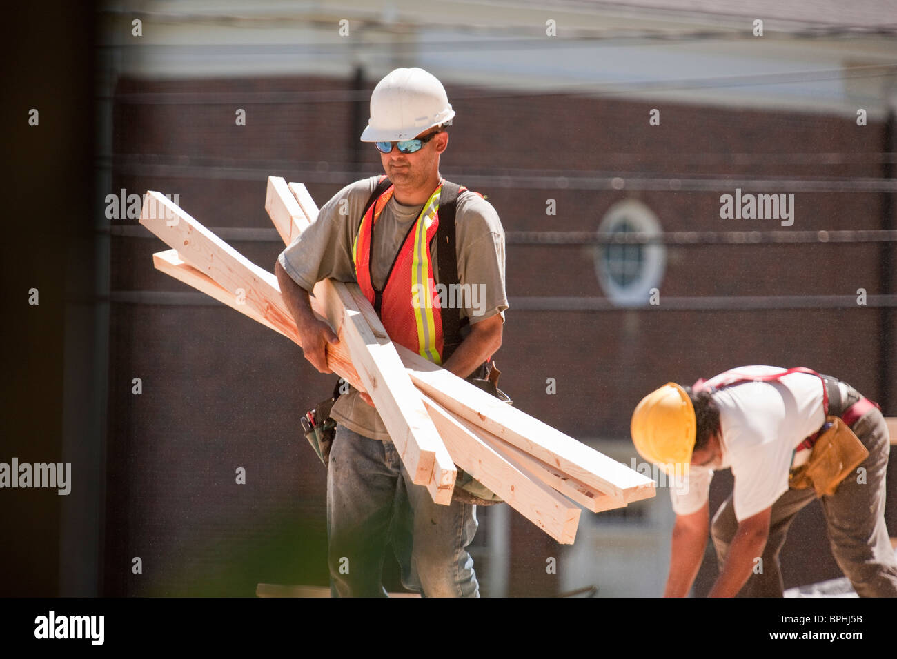 Carpenters carrying wood planks at a construction site Stock Photo - Alamy