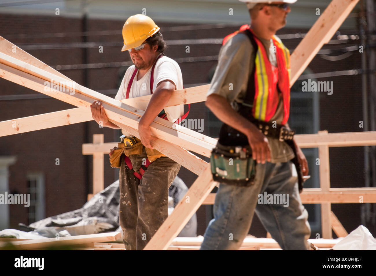 Carpenters carrying wood planks at a construction site Stock Photo - Alamy