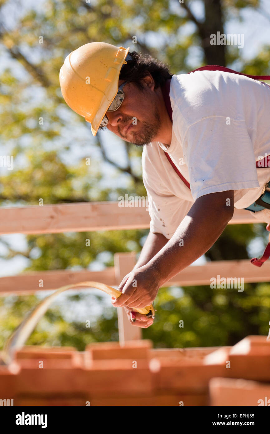Carpenter measuring planks with tape measure at a construction site ...