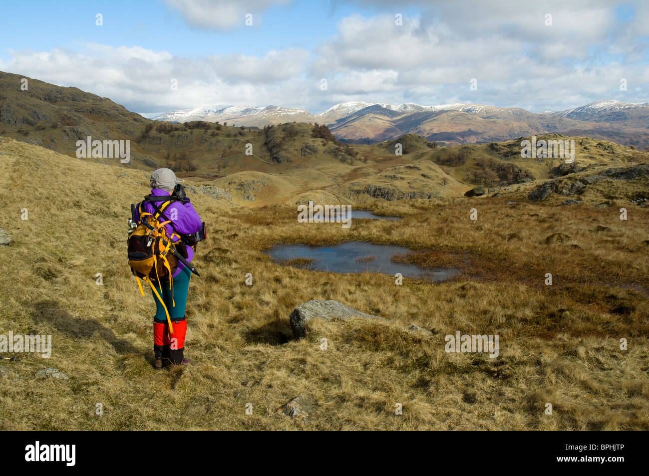 A walker photographs the distant Helvellyn range from Wetherlam ...