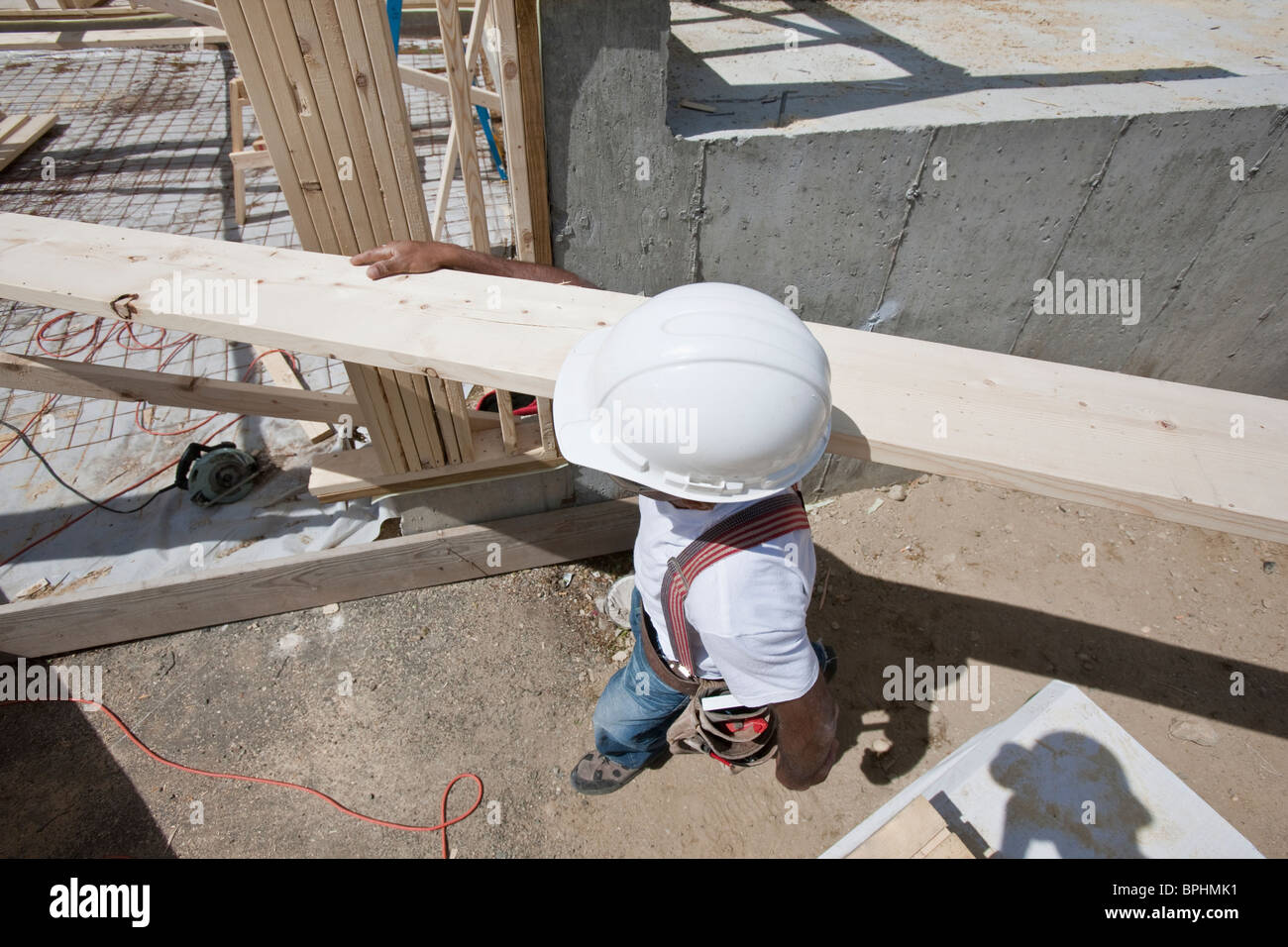 Carpenter carrying a plank at a construction site Stock Photo - Alamy