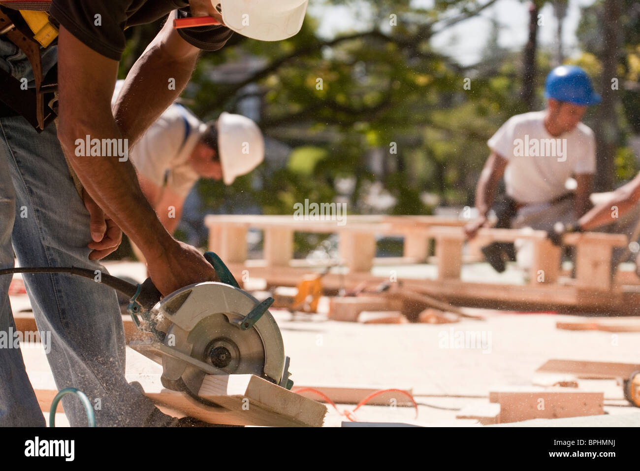Carpenters using circular saw at a construction site with gable frame ...