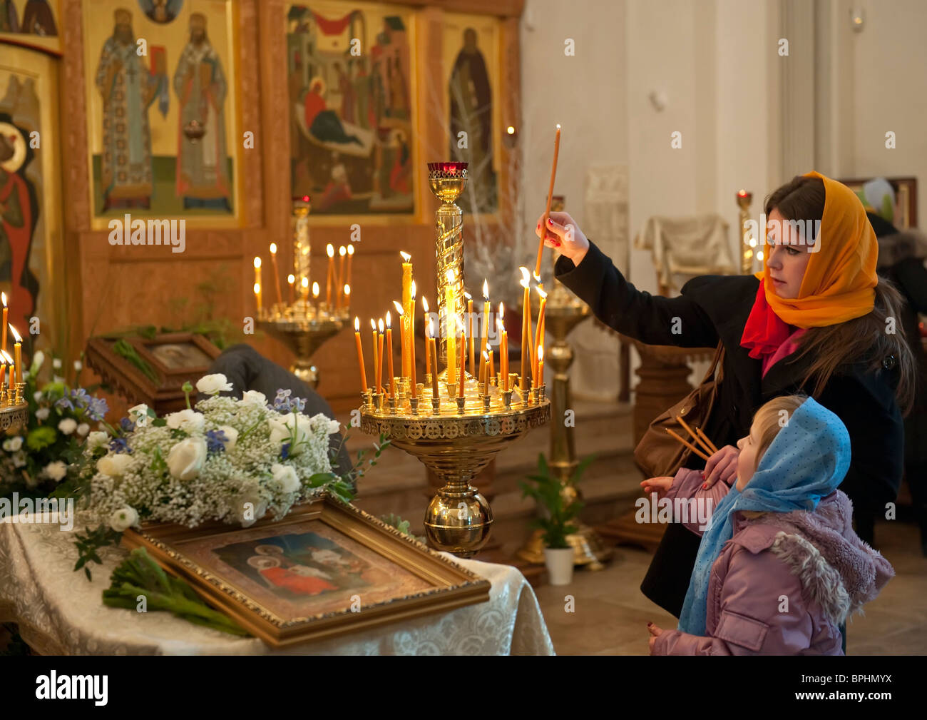 A woman and a child light a candle in the Russian Orthodox Church ...