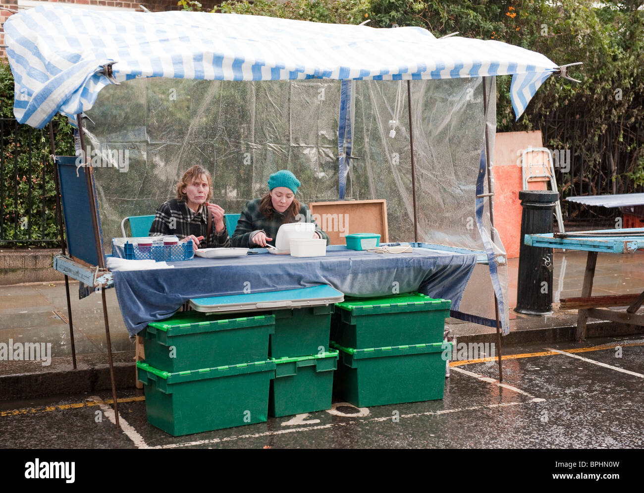 Two stallholders eating in their stall on a rainy dayPortobello Market ...