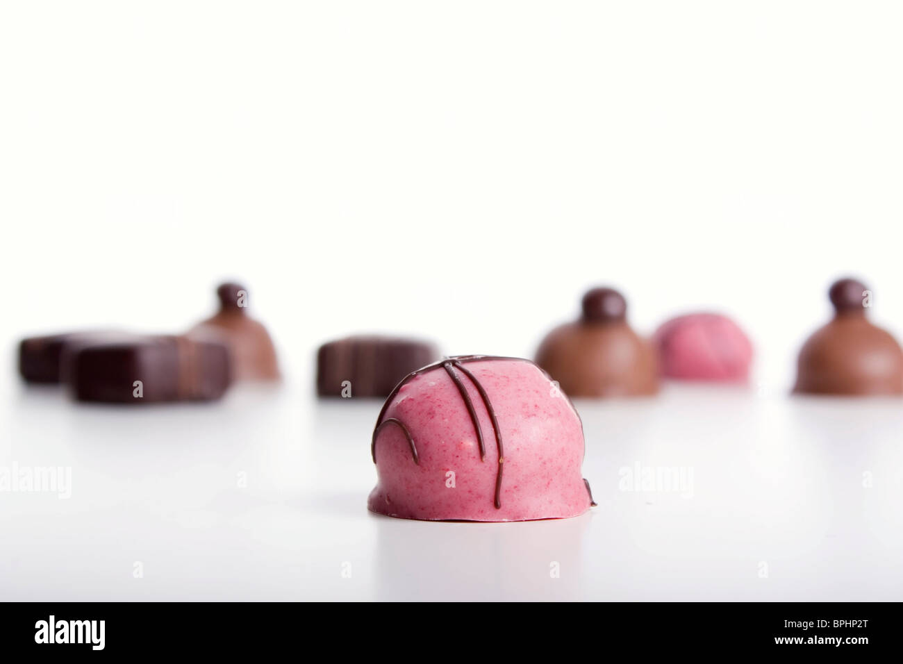 Raspberry flavored candy close up with more chocolates in distance ...