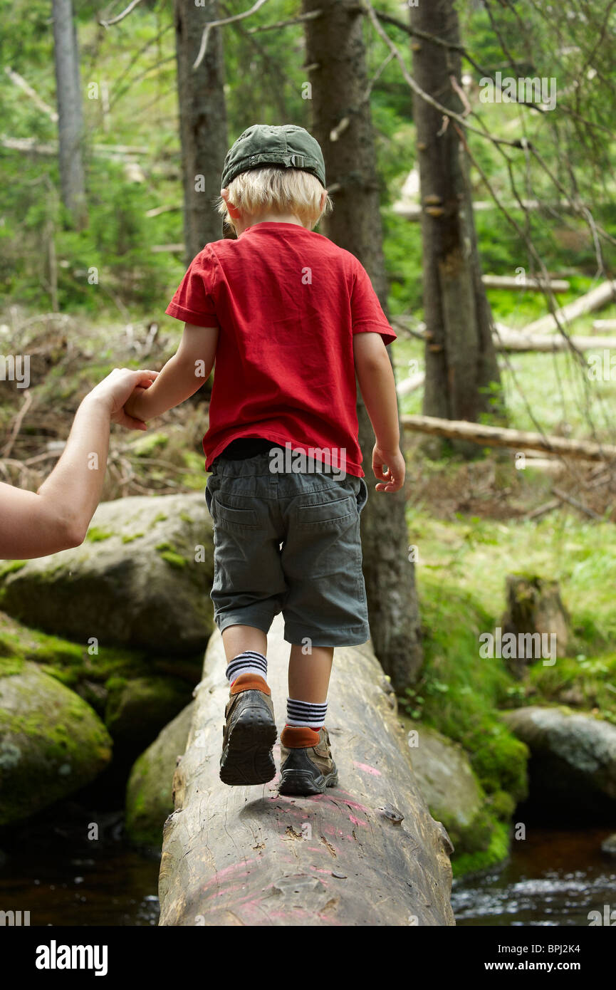 Children exploring in forest - mother helping son over stream ...