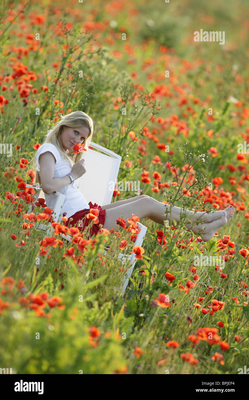 Young woman sitting on a chair in the middle of a poppy field Stock ...