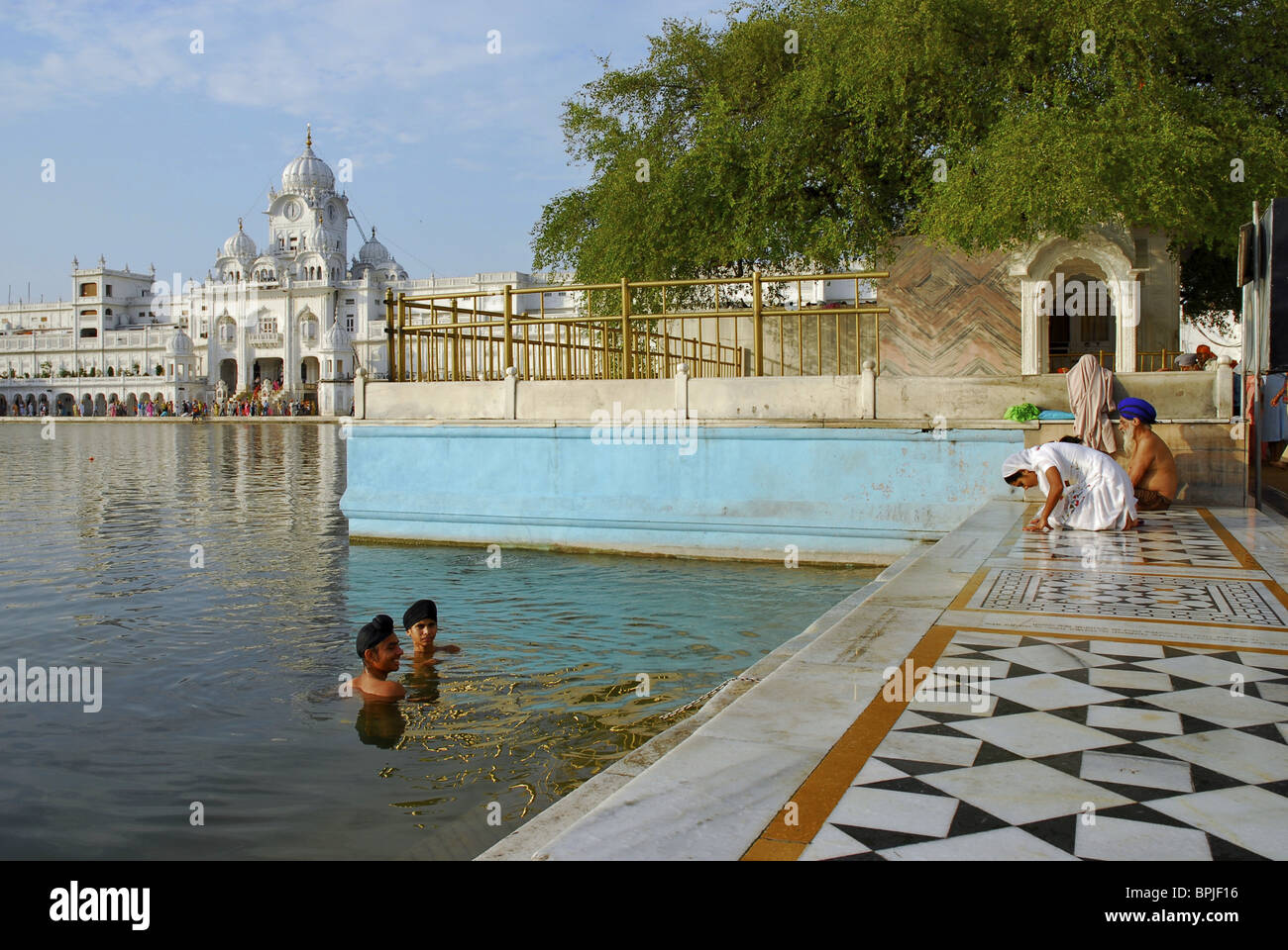 Golden Temple, two young Sikh men bathing in the holy lake, Sikh holy ...