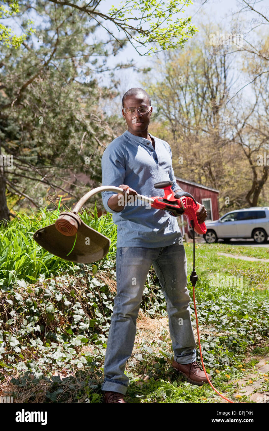 Black man holding weed trimmer Stock Photo - Alamy
