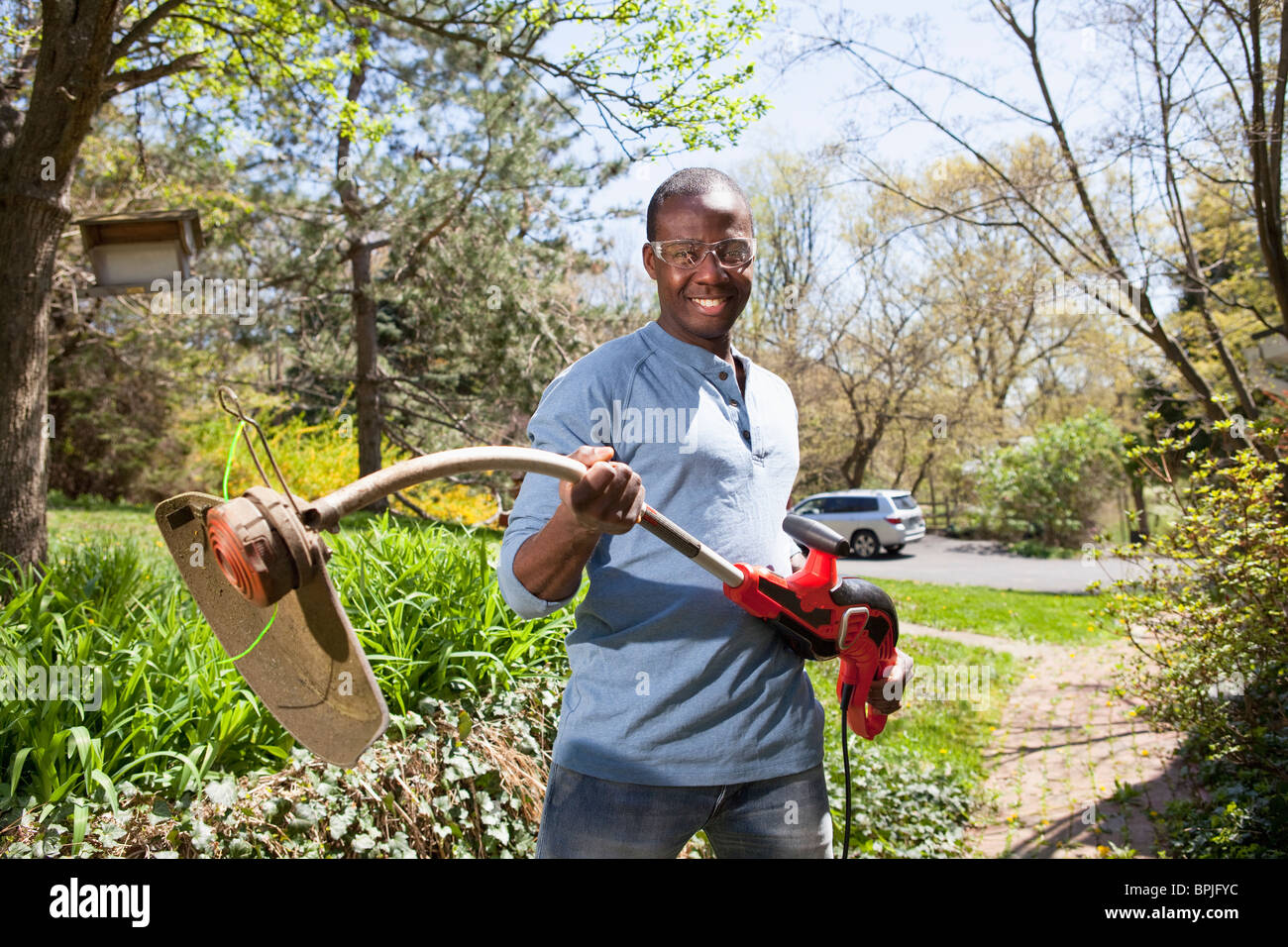 Black man holding weed trimmer Stock Photo - Alamy