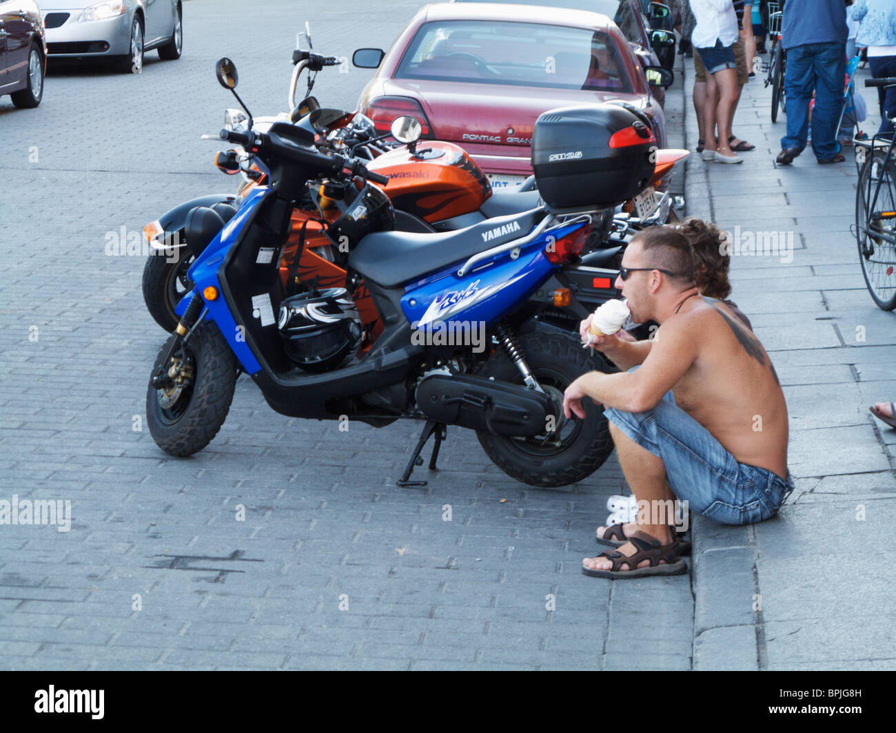 Man sitting on curb eating ice cream cone. Rue de la Commune. Montreal ...