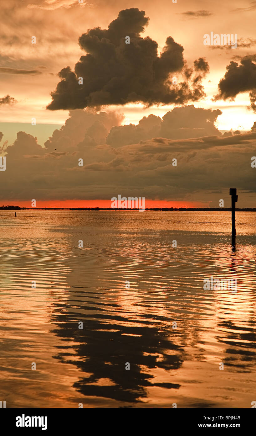 Storm clouds reflected in water at sunset Stock Photo - Alamy