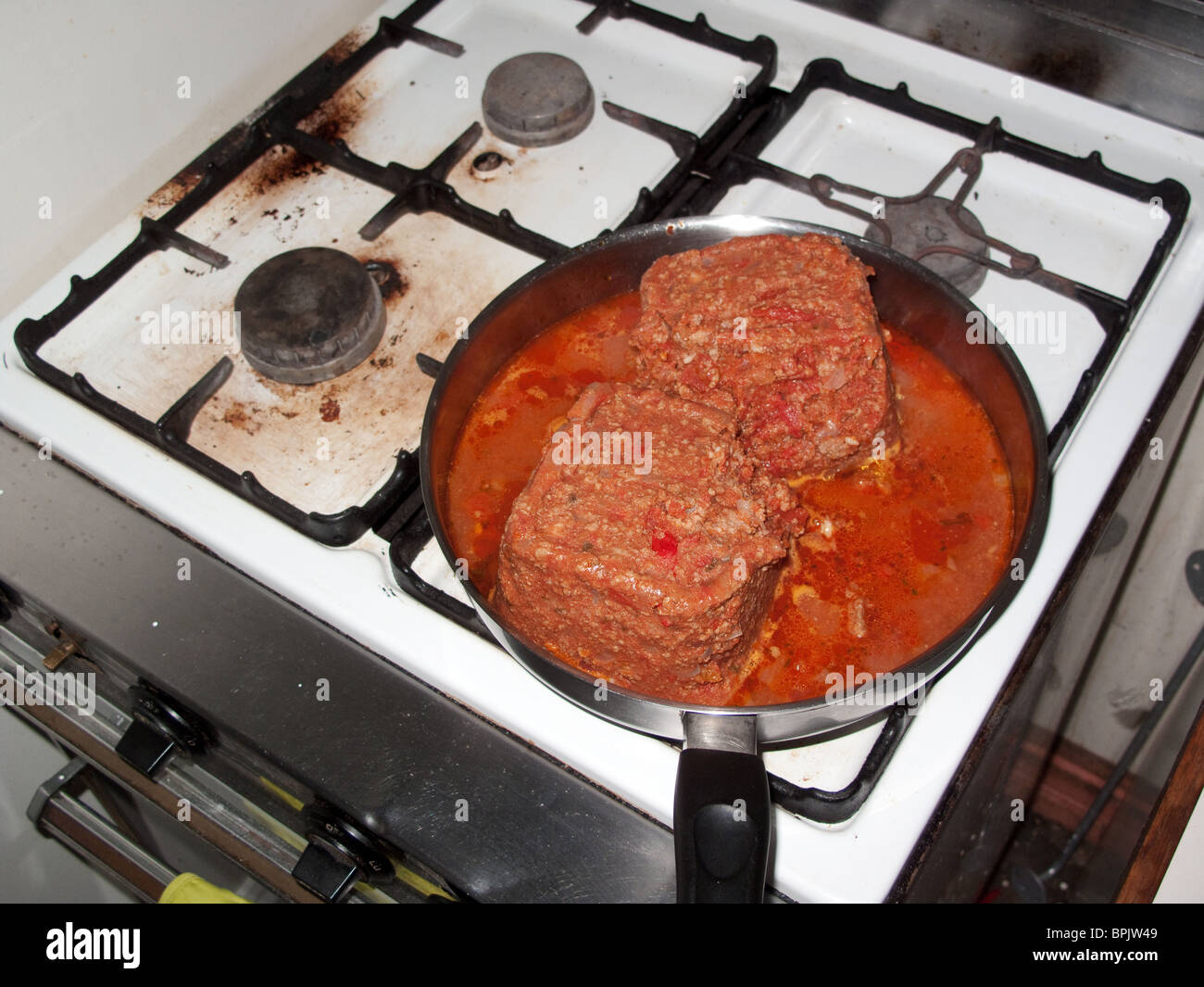 Frozen marinara spaghetti pasta sauce thawing in a frying pan on a ...