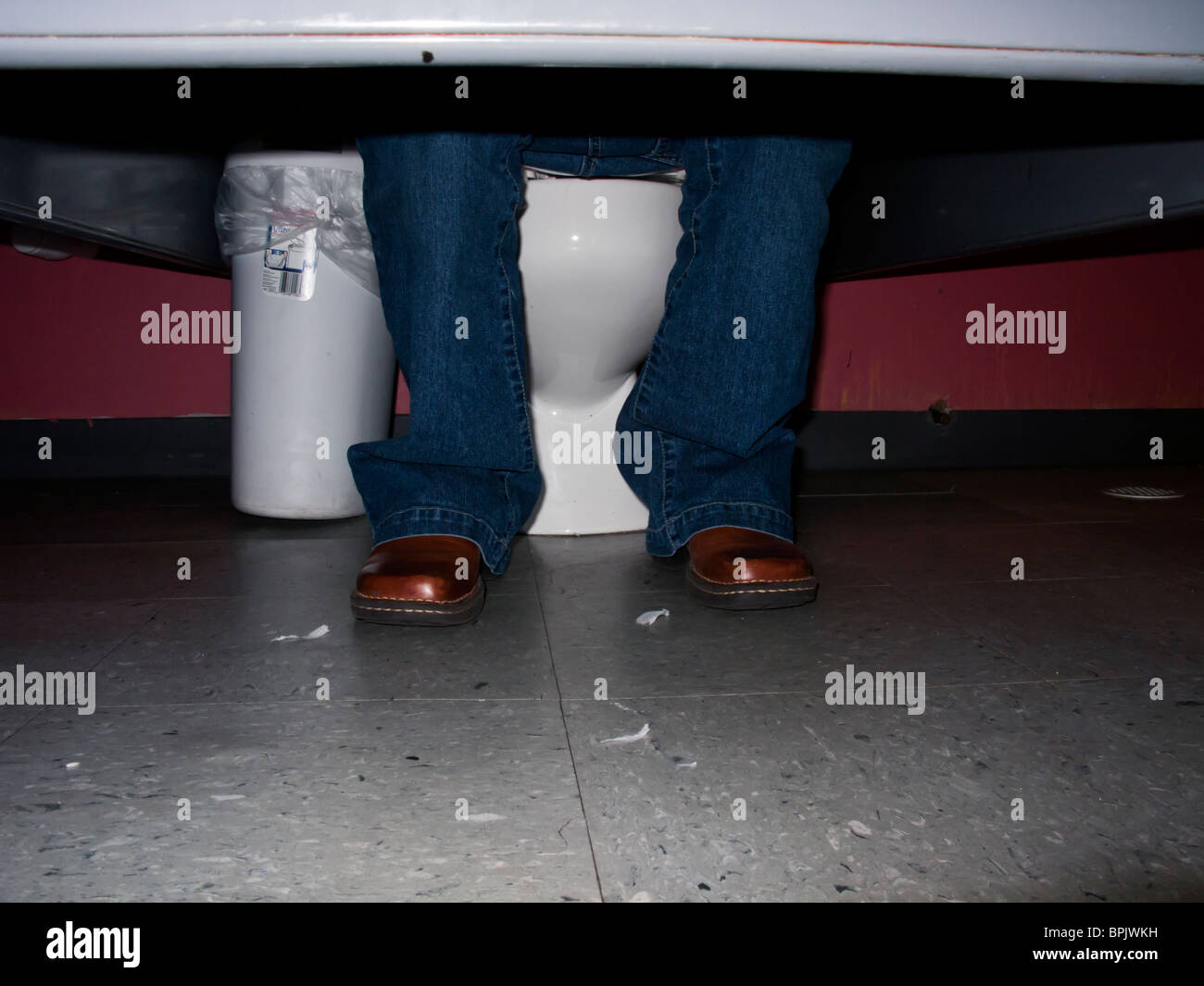 A woman sits inside a public restroom stall, showing legs only Stock ...