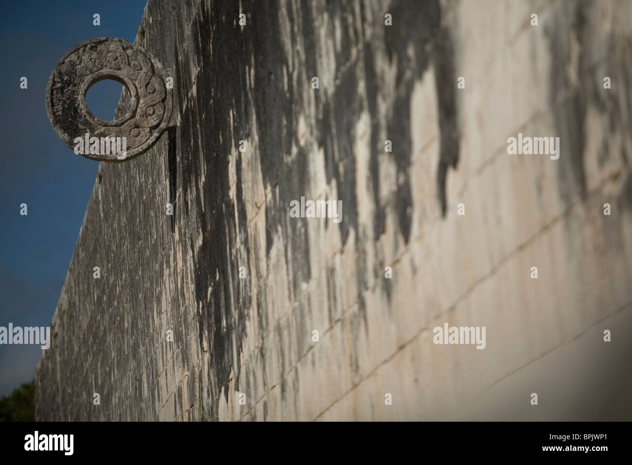A stone ring juts out from the side of a ball court's wall among the ...