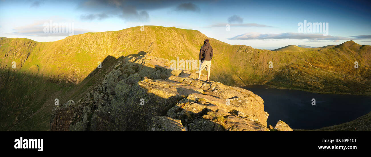 Walker on the narrow ridge of Striding Edge at dawn in the English Lake ...