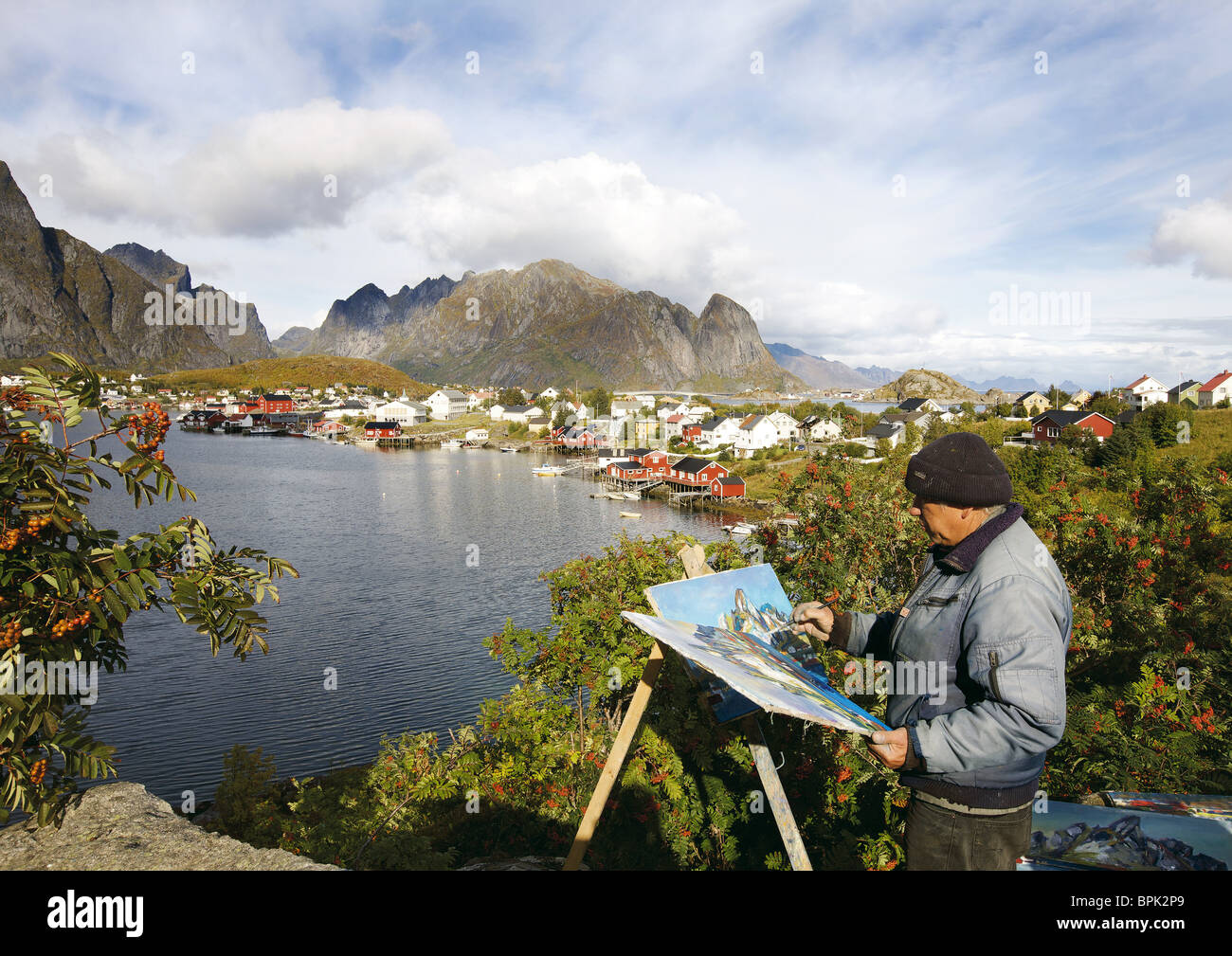 Norwegian painter in front of the coastal village Reine, Lofoten ...