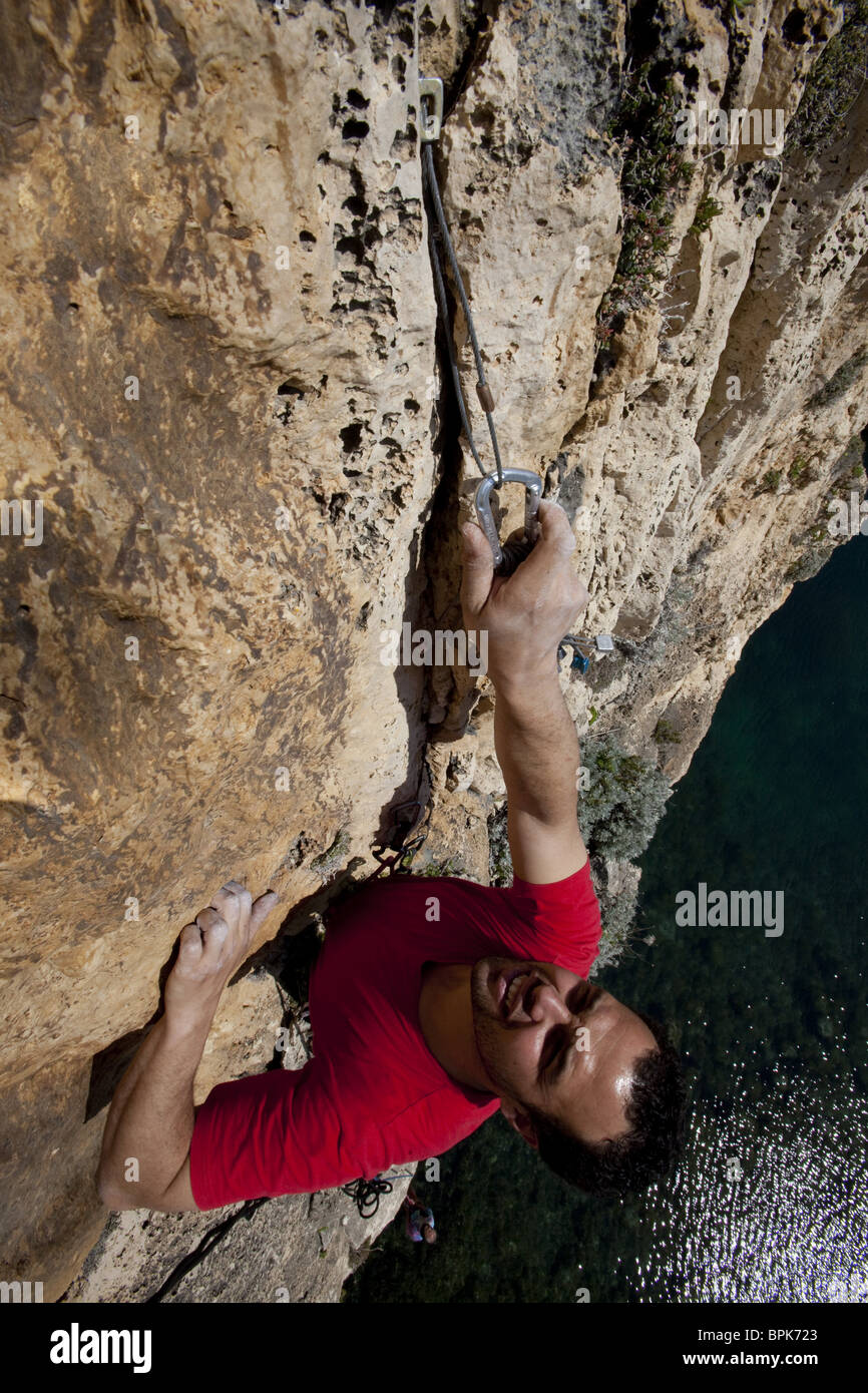 A young man climbing above the Inland Sea, he places natural protection ...