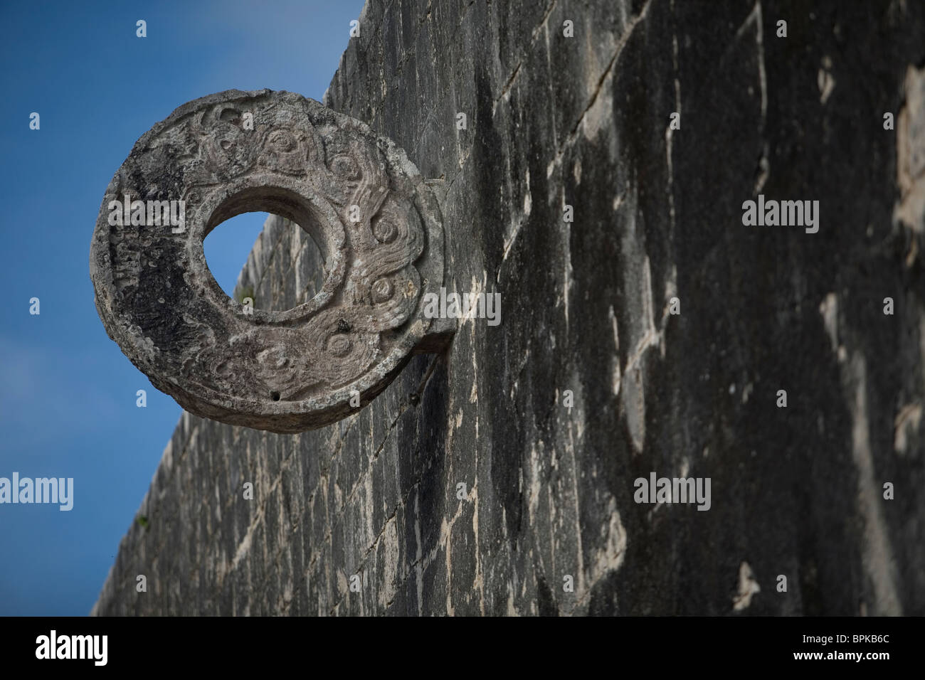 A stone ring juts out from the side of a ball court's wall among the ...