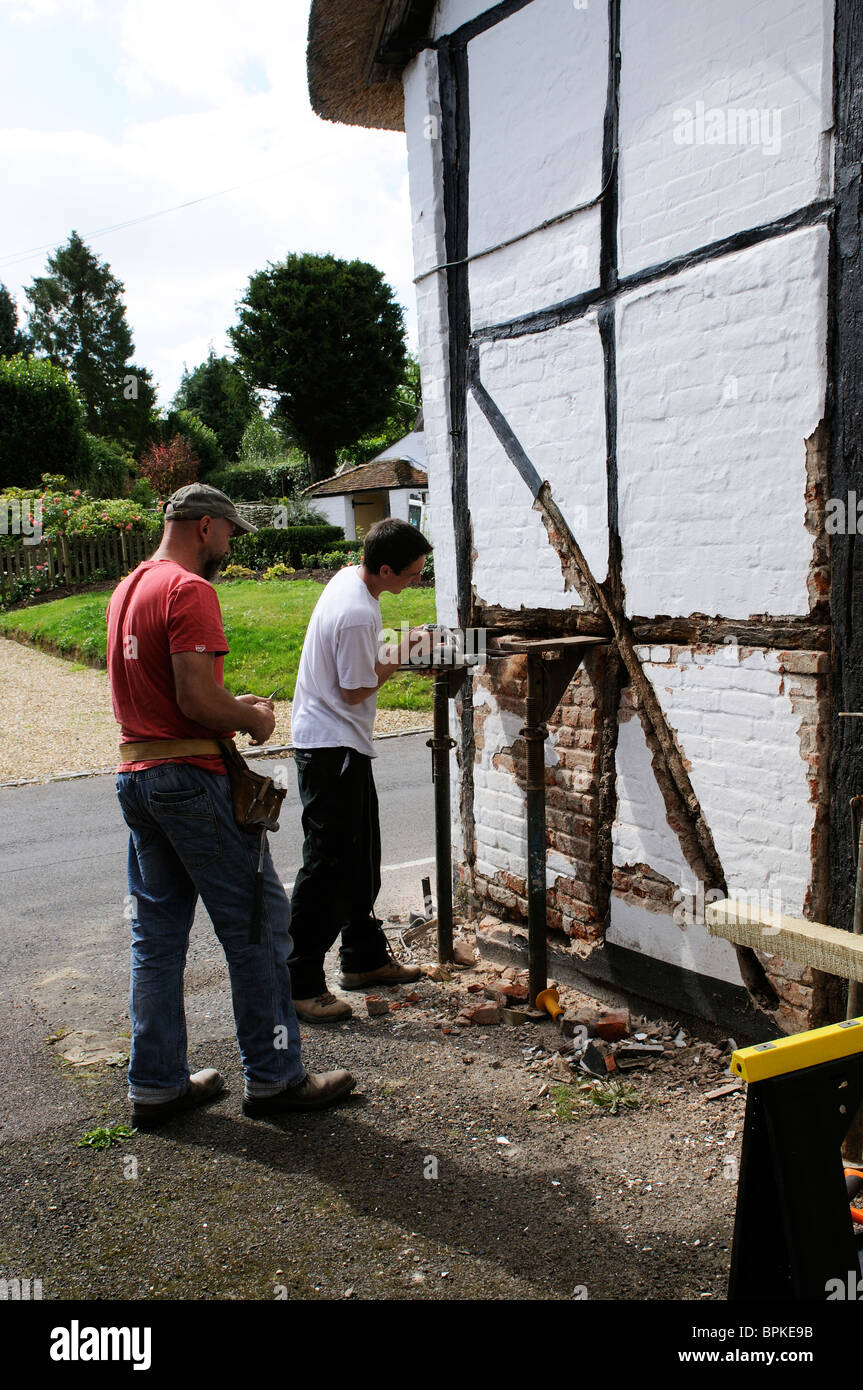 Renovating an old timber framed listed building Workman removing bricks ...