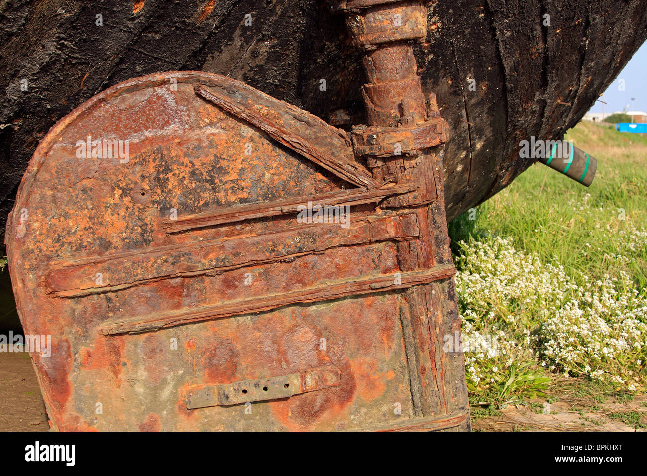 The rotting stern of an old fishing boat with its rusty rudder and ...