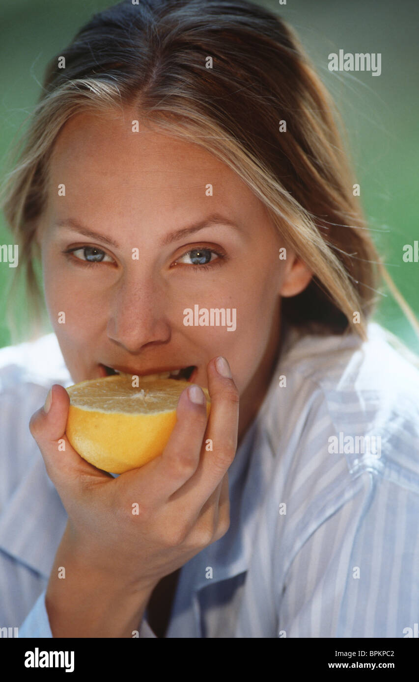 Young woman eating lemon Stock Photo - Alamy