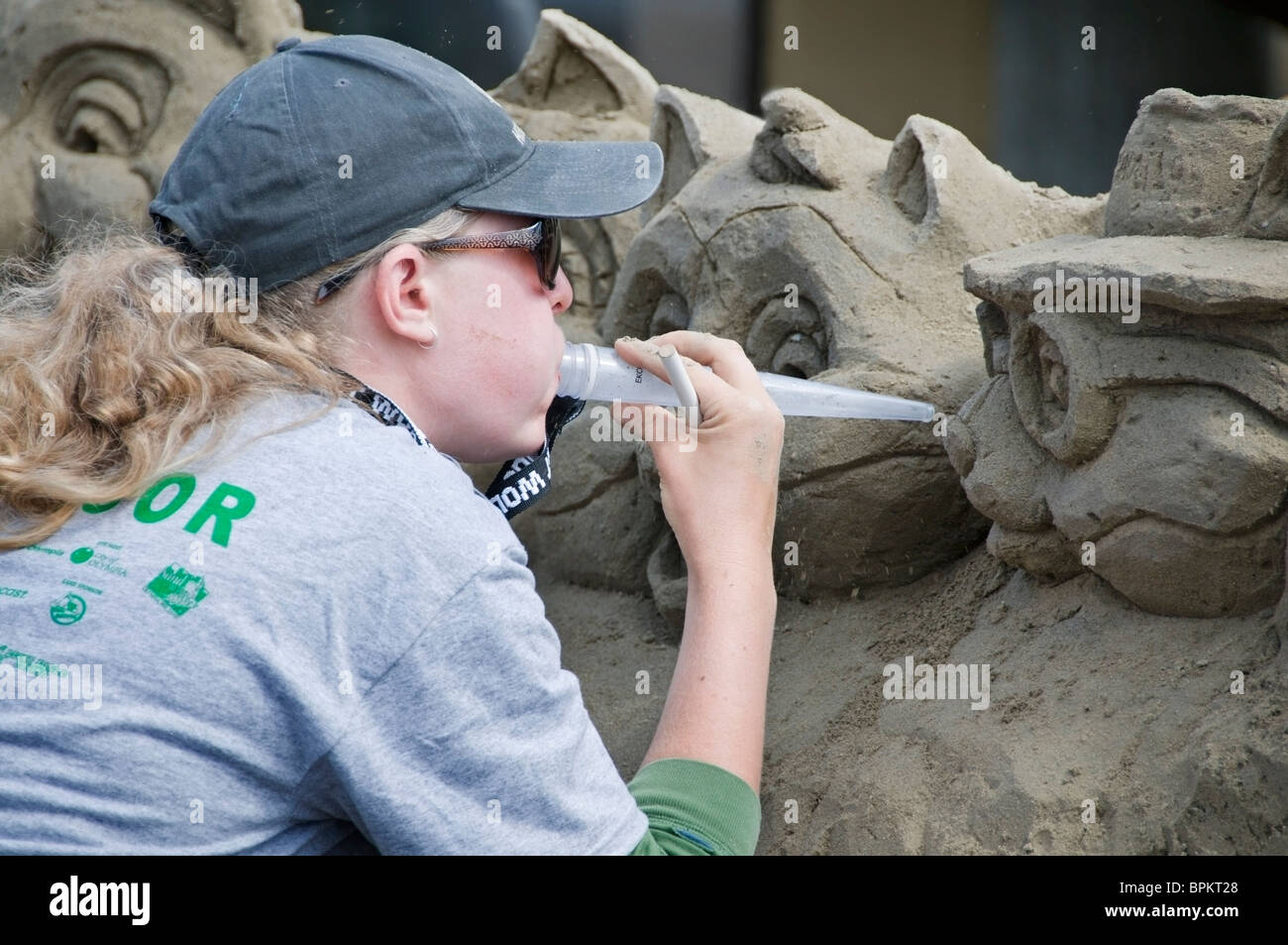 A sand sculptor blows sand away from a nearly complete work of art at ...