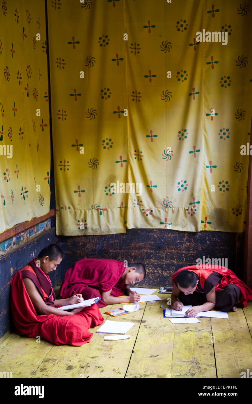Three Buddhist monks study and write in a room draped with yellow ...