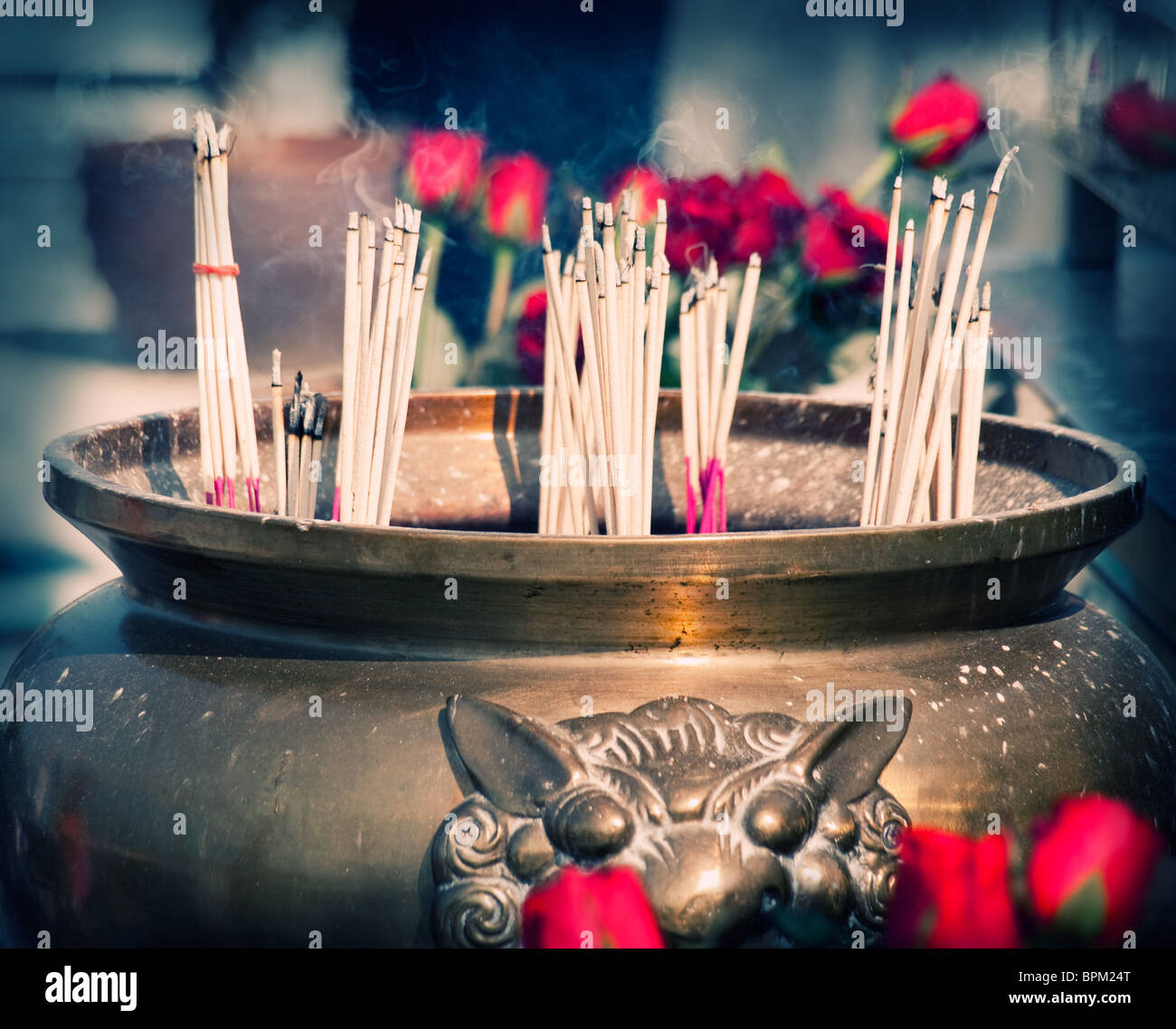 Buddhist shrine with smoking incense sticks and roses, cross-processed image , closeup Stock ...