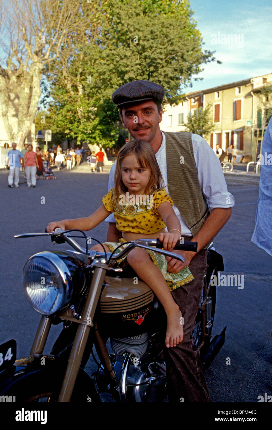 French father and daughter sitting on motorcycle, festival, town of ...