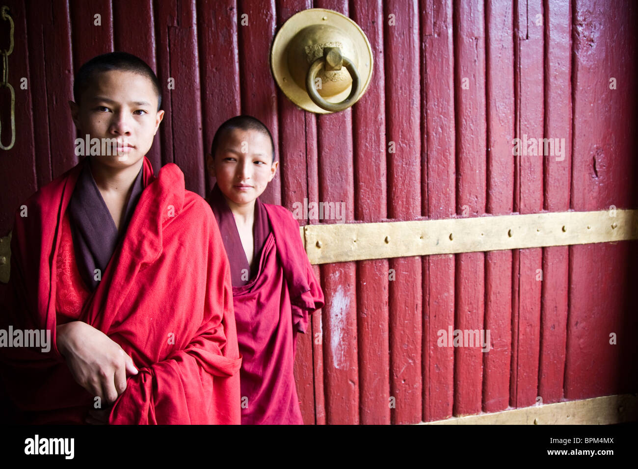 Two young Buddhist monks stand before an ancient monastery door Bhutan ...