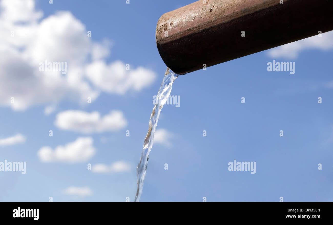 Water is falling from pipe, sky background Stock Photo - Alamy