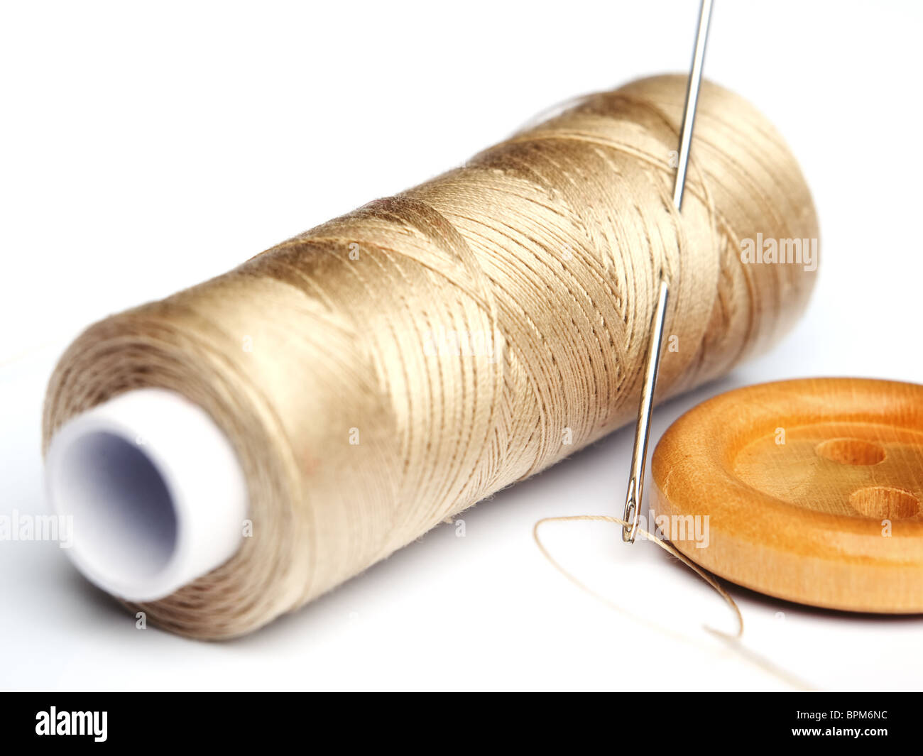 Thread, needle and button on a white background can suggest fashion ...