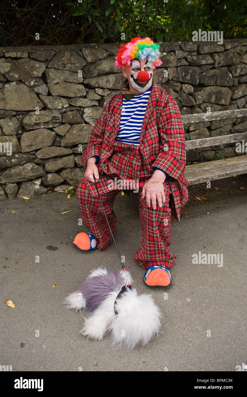 Clown sitting on bench with toy dog in the street during Llandrindod ...