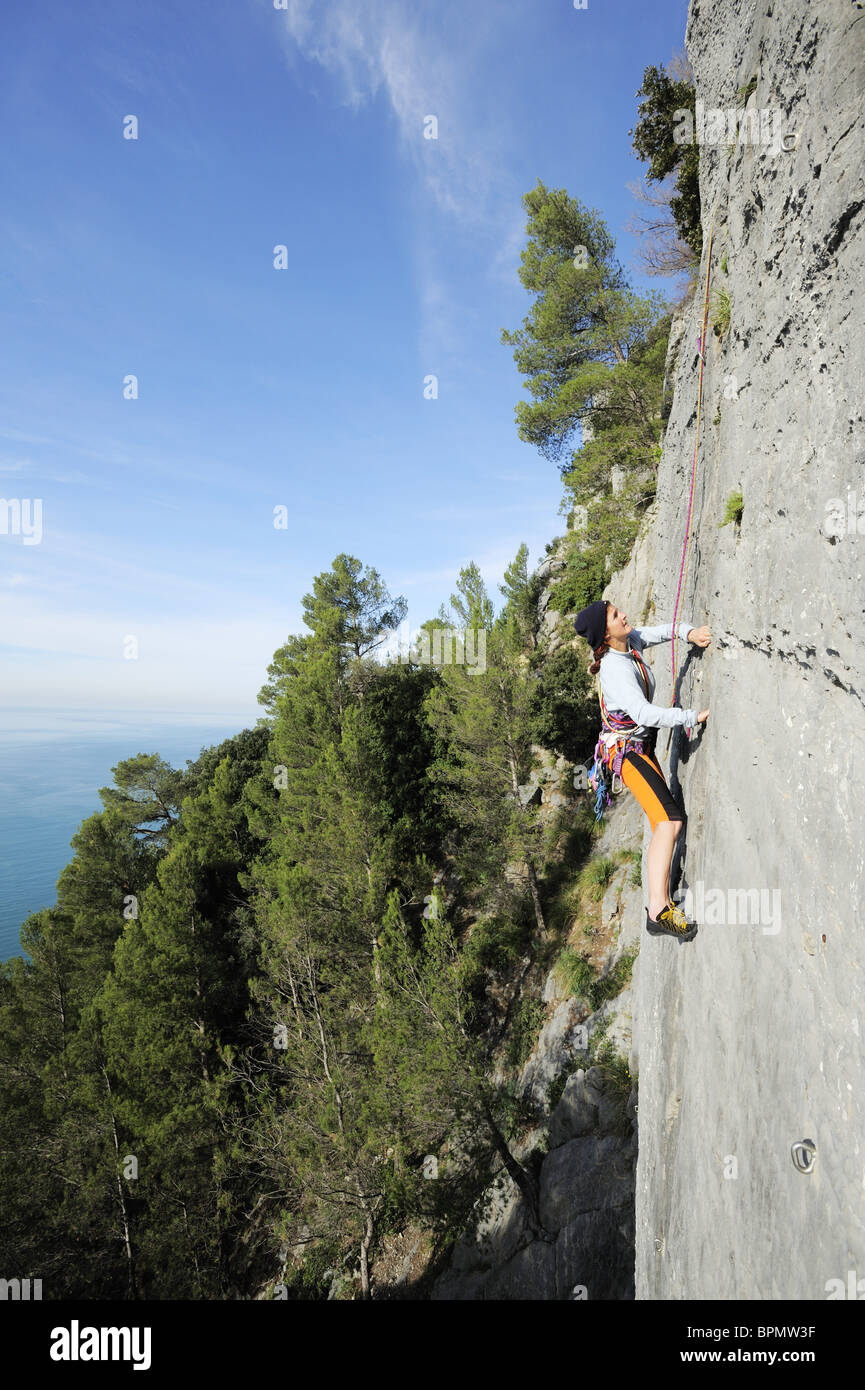 Woman climbing a steep rock face at the Mediterranean, natural park ...