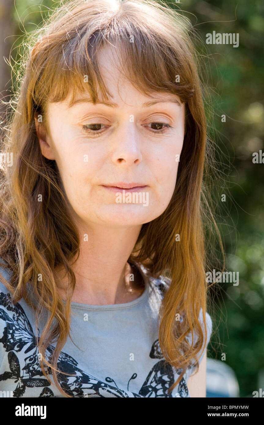 Woman looking downcast with long brown hair Stock Photo - Alamy