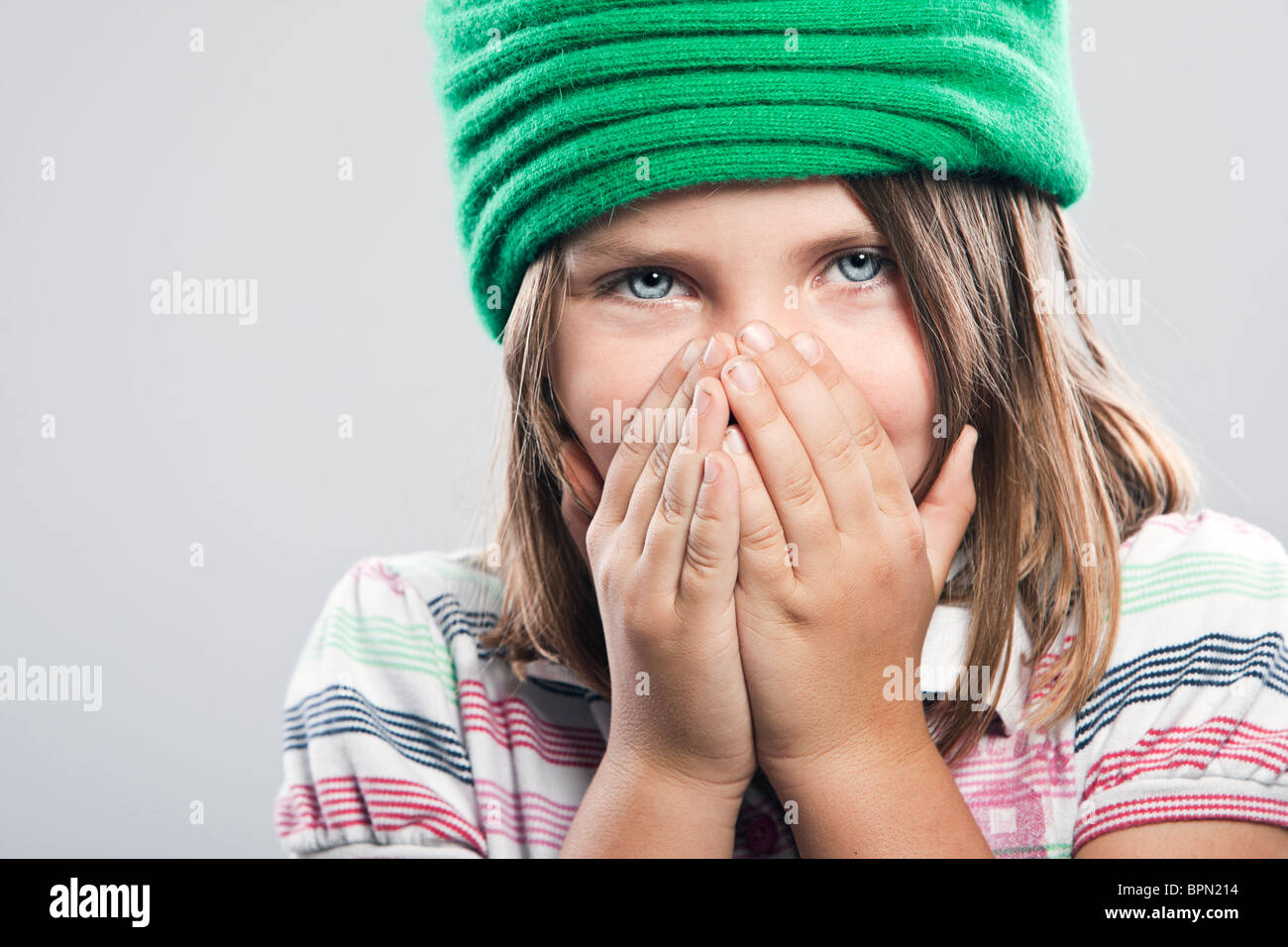 Shot of a Cute Child with Green Hat Covering her Mouth and Nose Stock ...