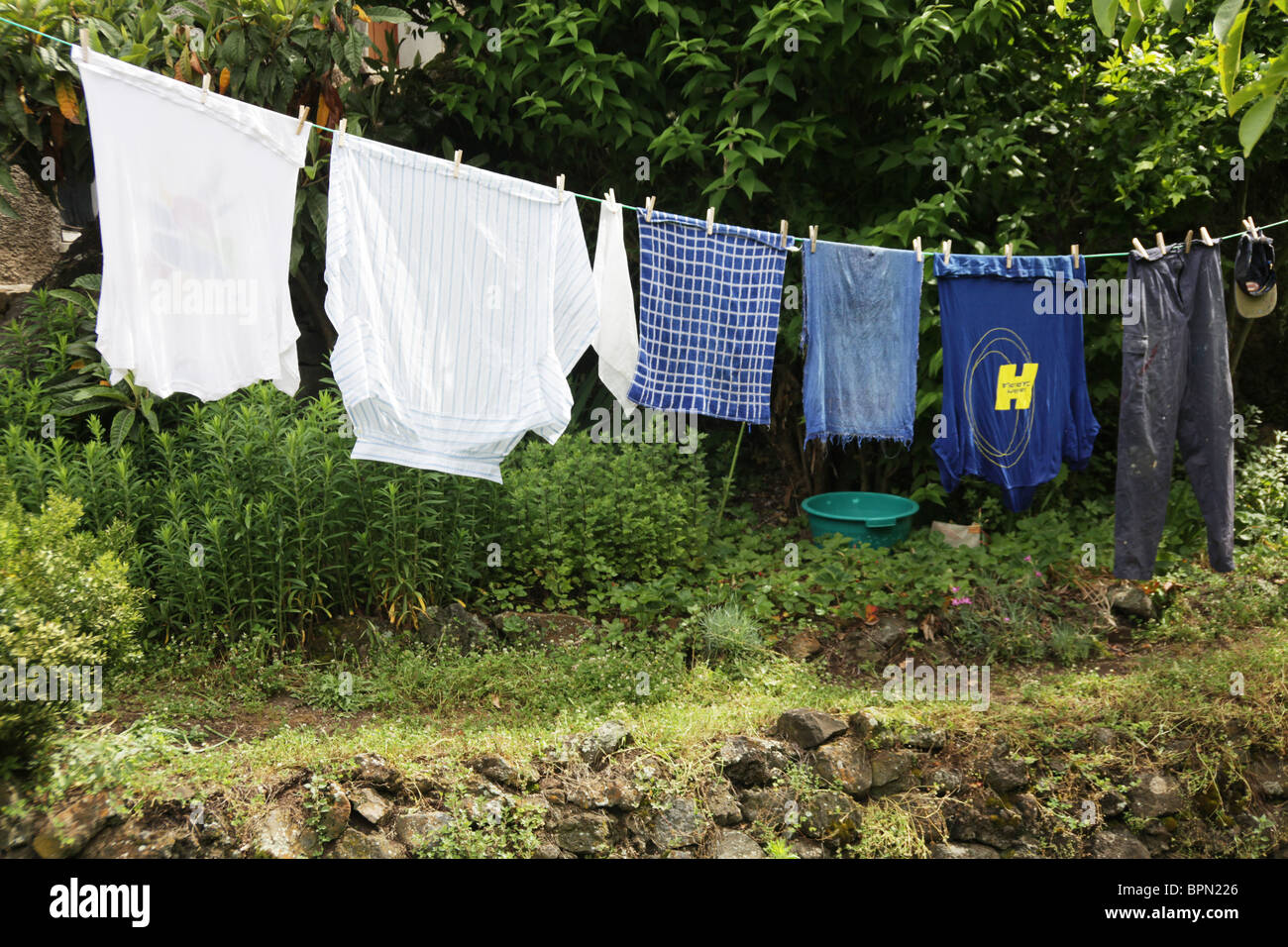 A farm worker's working clothes hanging on a washing line in a farmyard ...
