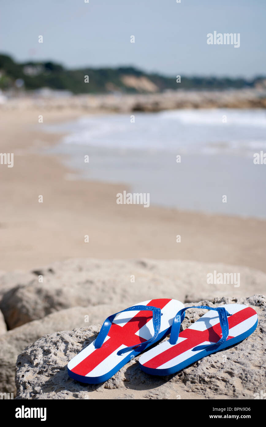 Pair of St George flip flops on a beach scene Stock Photo - Alamy
