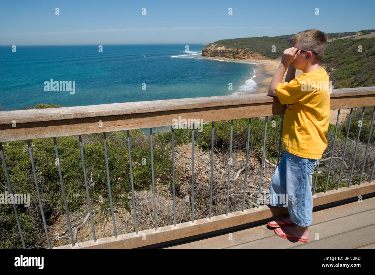 Little boy standing on a balcony looking out towards the sea Stock ...