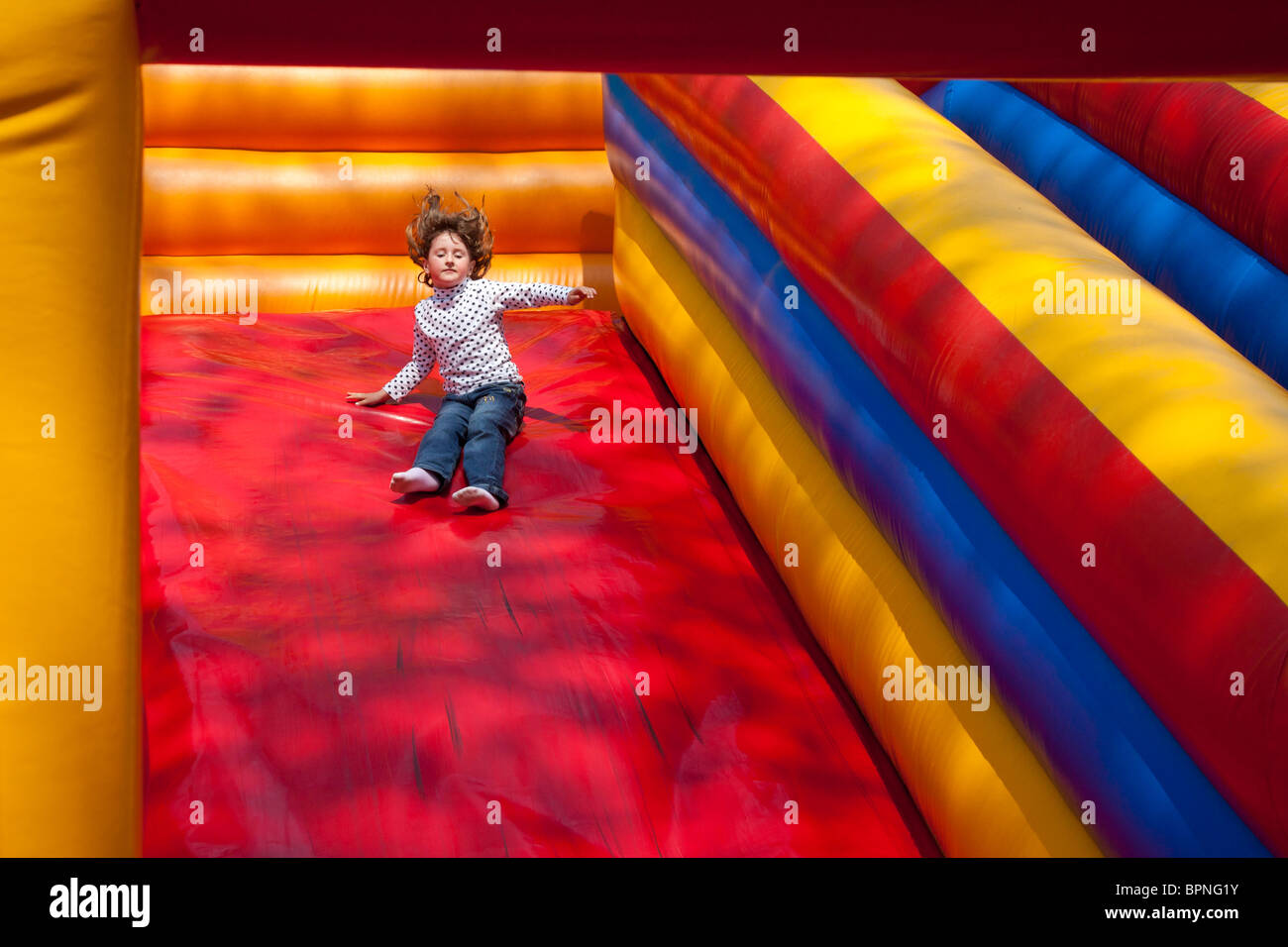 Little girl having fun on a blown up slider Stock Photo - Alamy