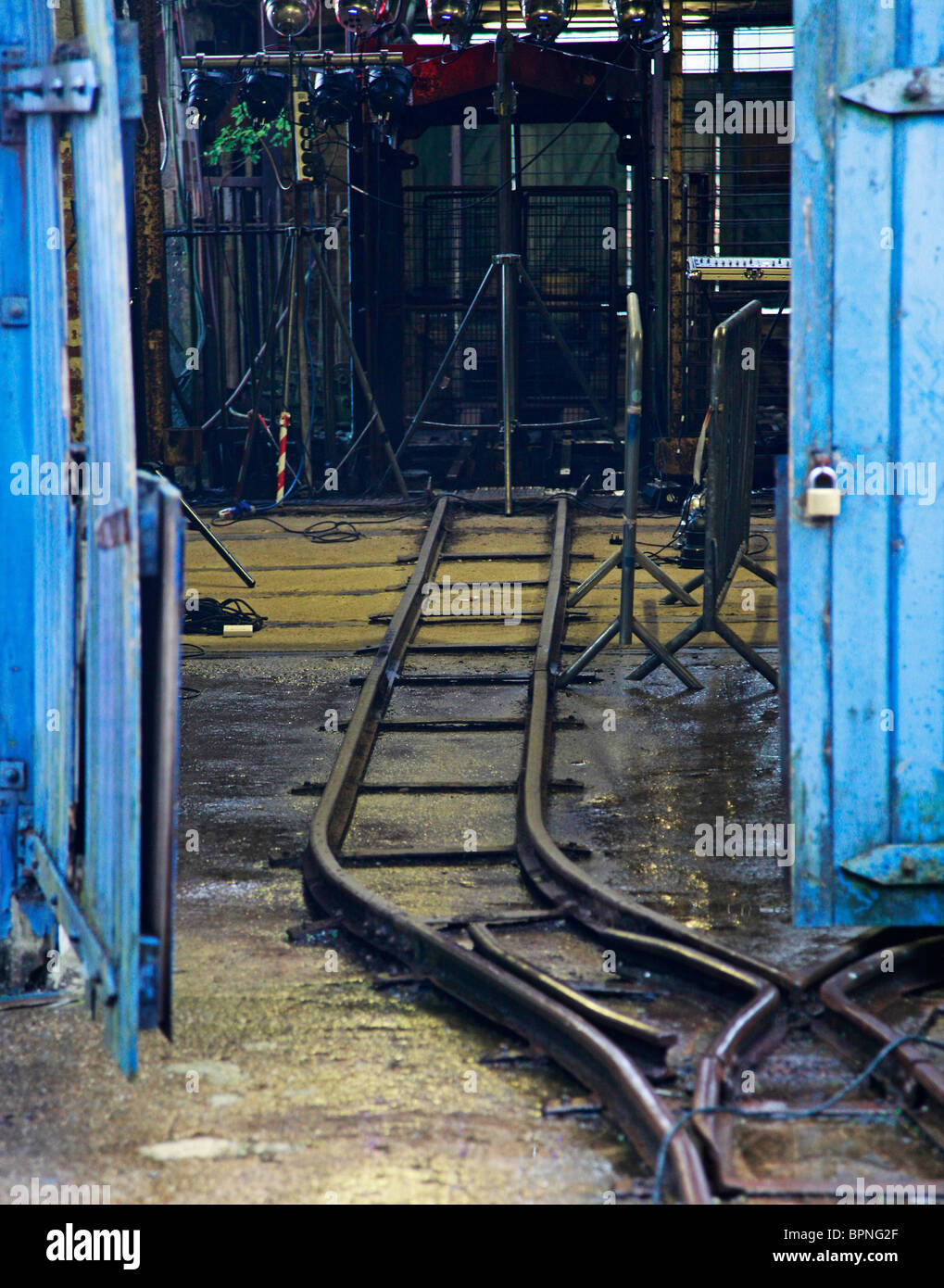 A railway track leading into an industrial building with blue doors ...