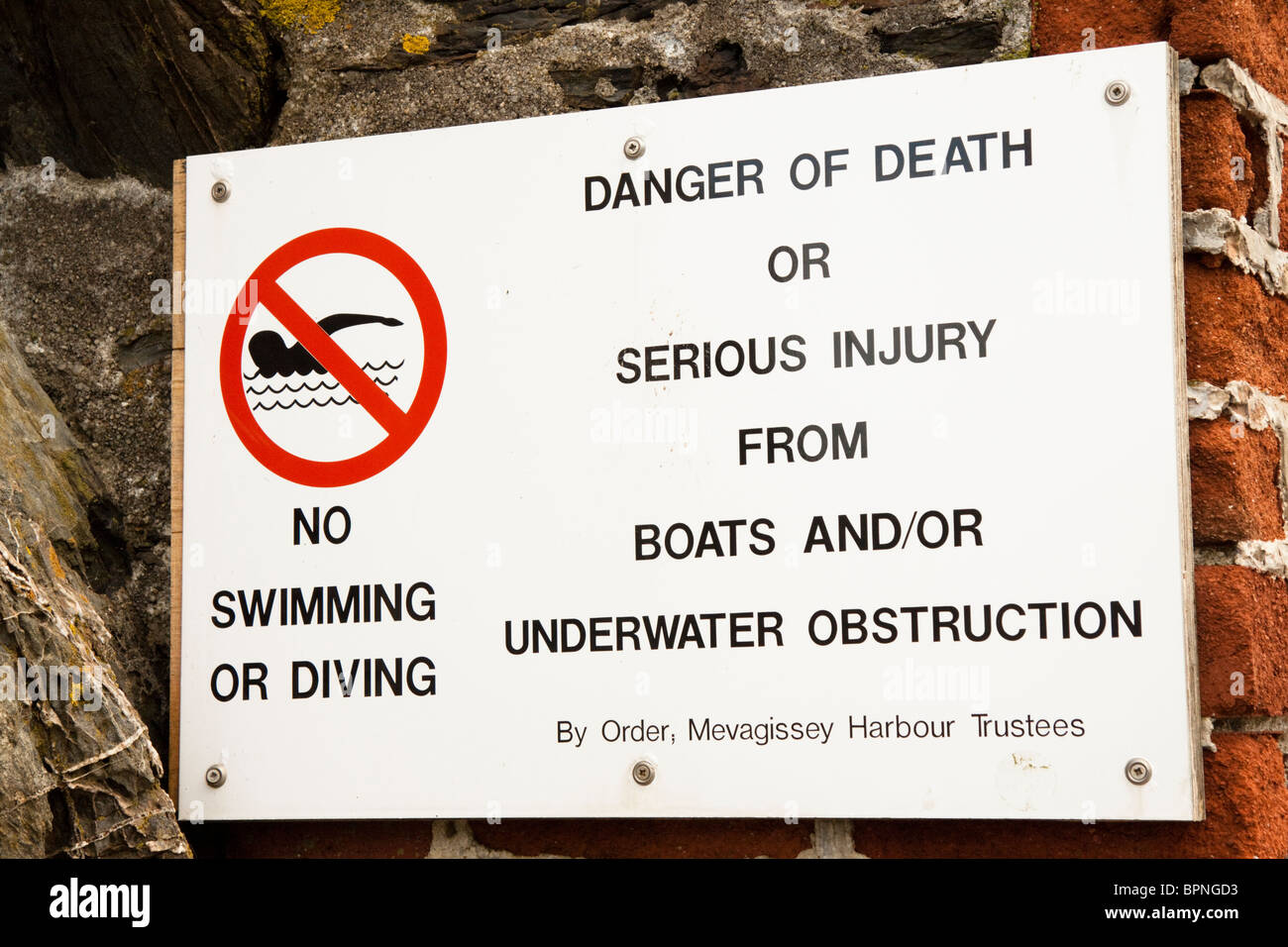 Sign on Mevagissey harbour wall warning against the dangers of swimming ...