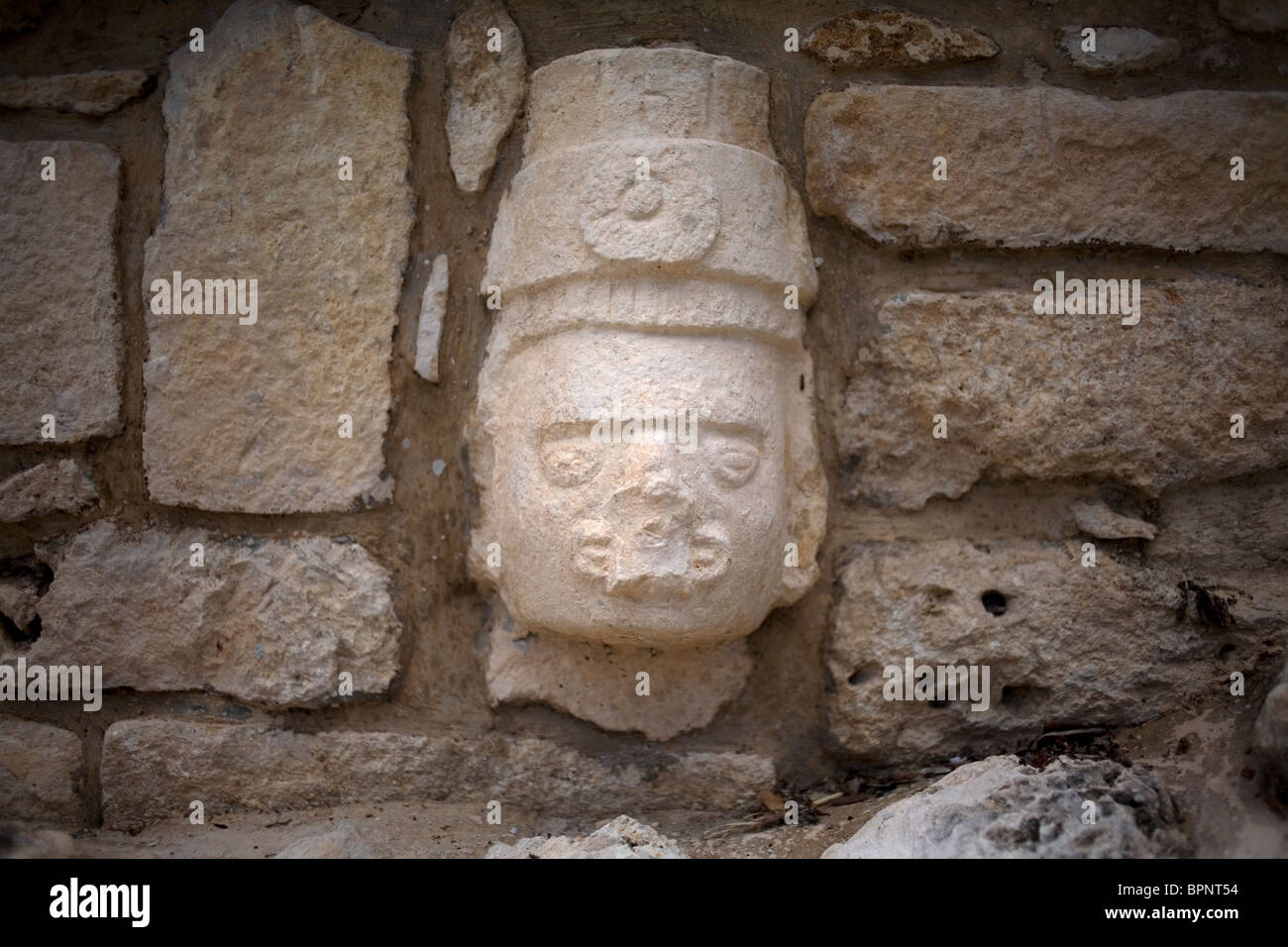 A sculpture of a human head decorates a temple of the Mayan ruins of ...