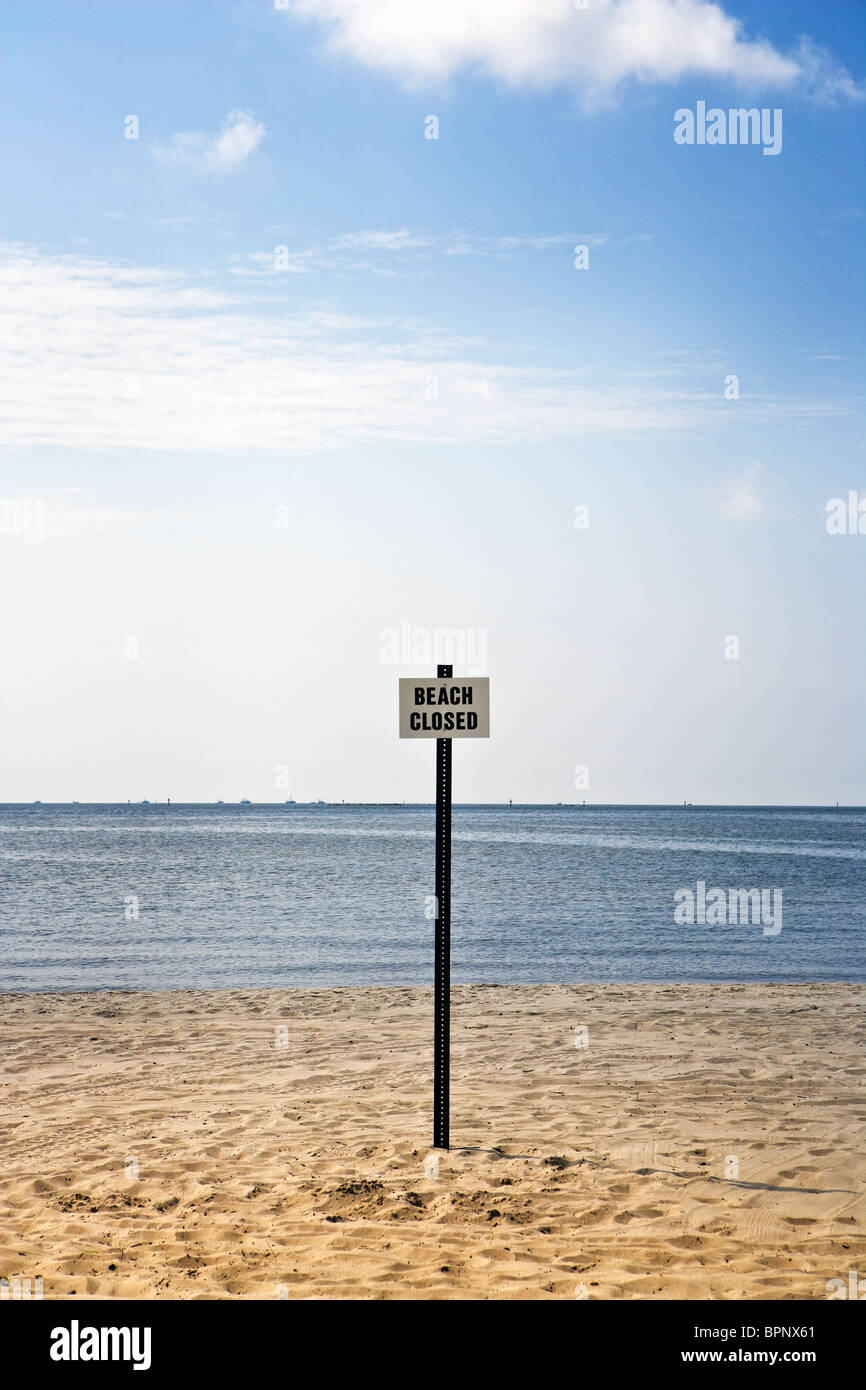 A 'Beach Closed' sign warns tourists while oil boom protects a small ...