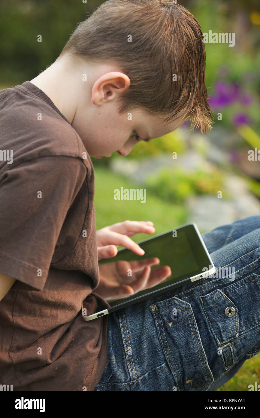 A 10 years old young boy using an iPad in the garden Stock Photo - Alamy